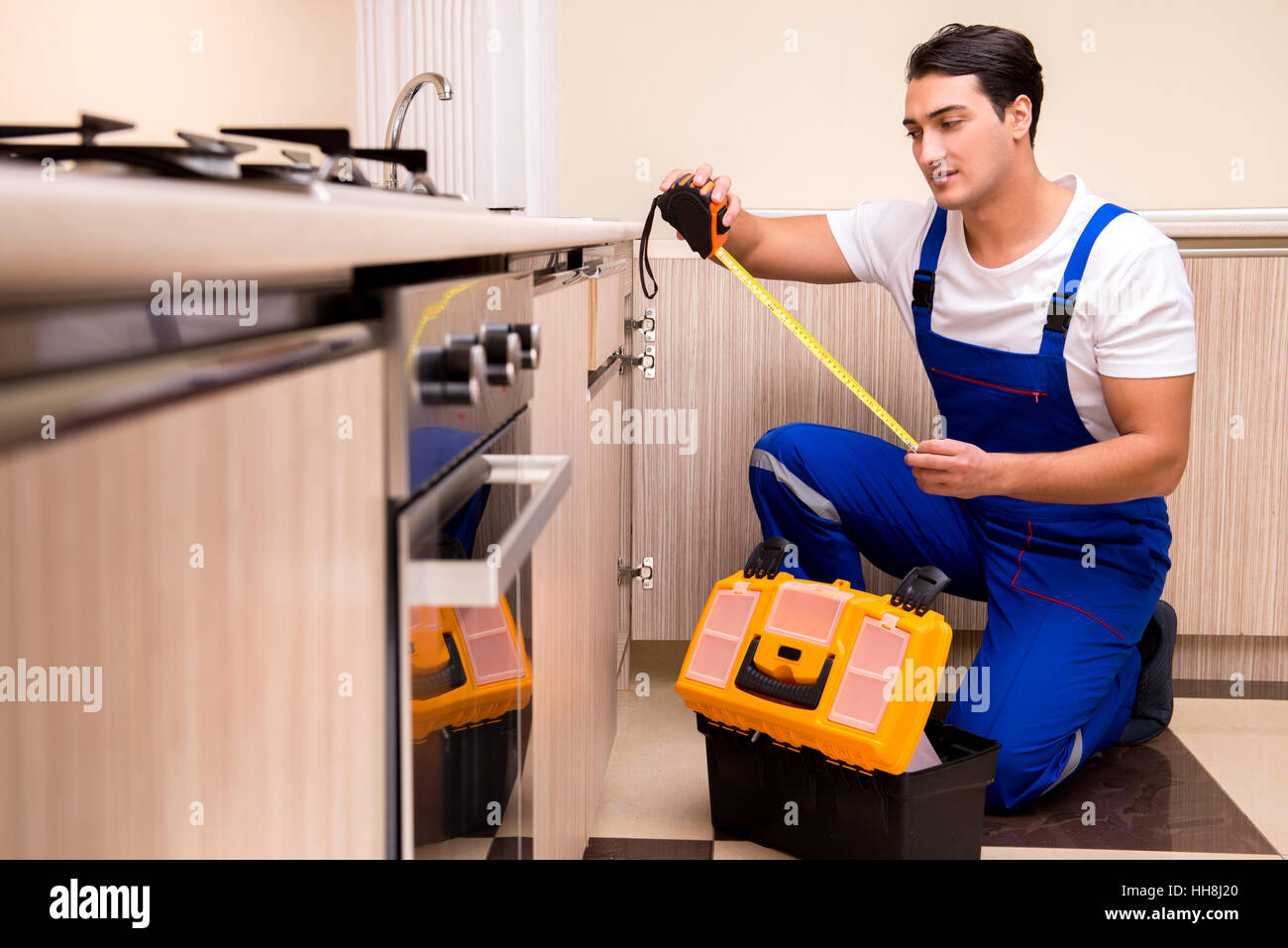 Young repairman working at the kitchen Stock Photo - Alamy