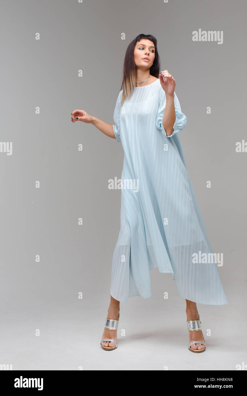 Woman make step in light long blue dress in studio Stock Photo - Alamy