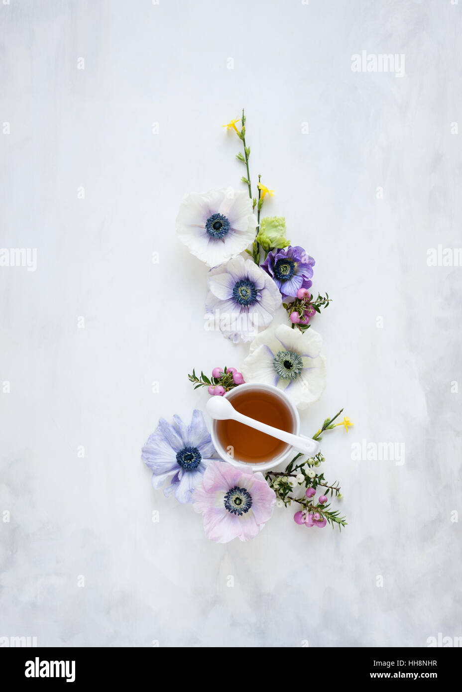 flat lay with spring flowers and teacup laid out on white and gray ...