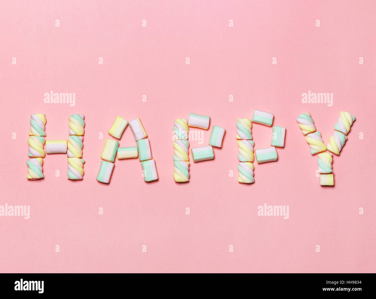 Multicolored letters HAPPY from marshmallow on gentle pink background ...