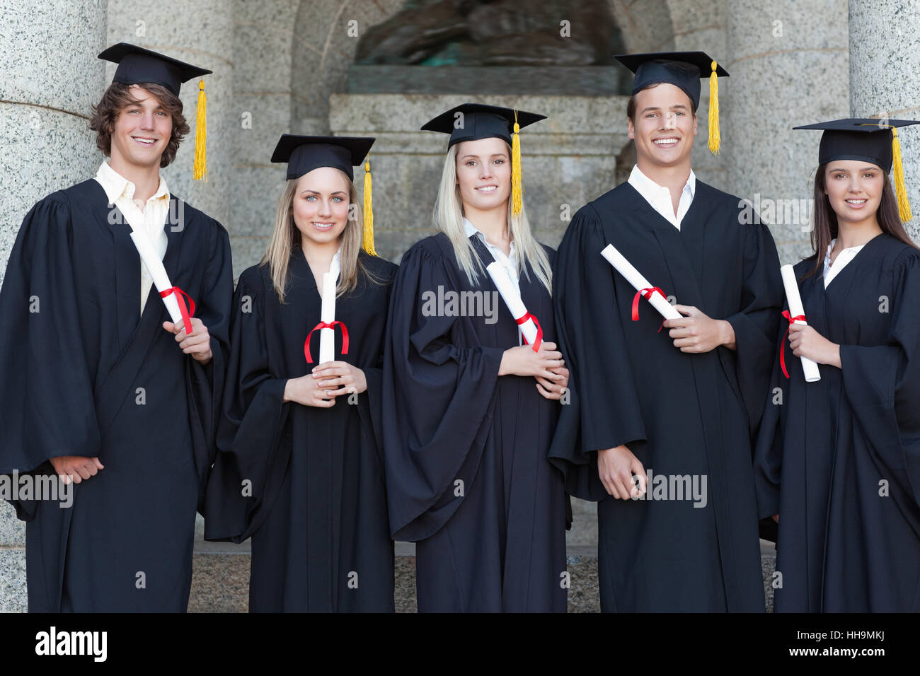 Smiling graduates posing in front of the university Stock Photo - Alamy