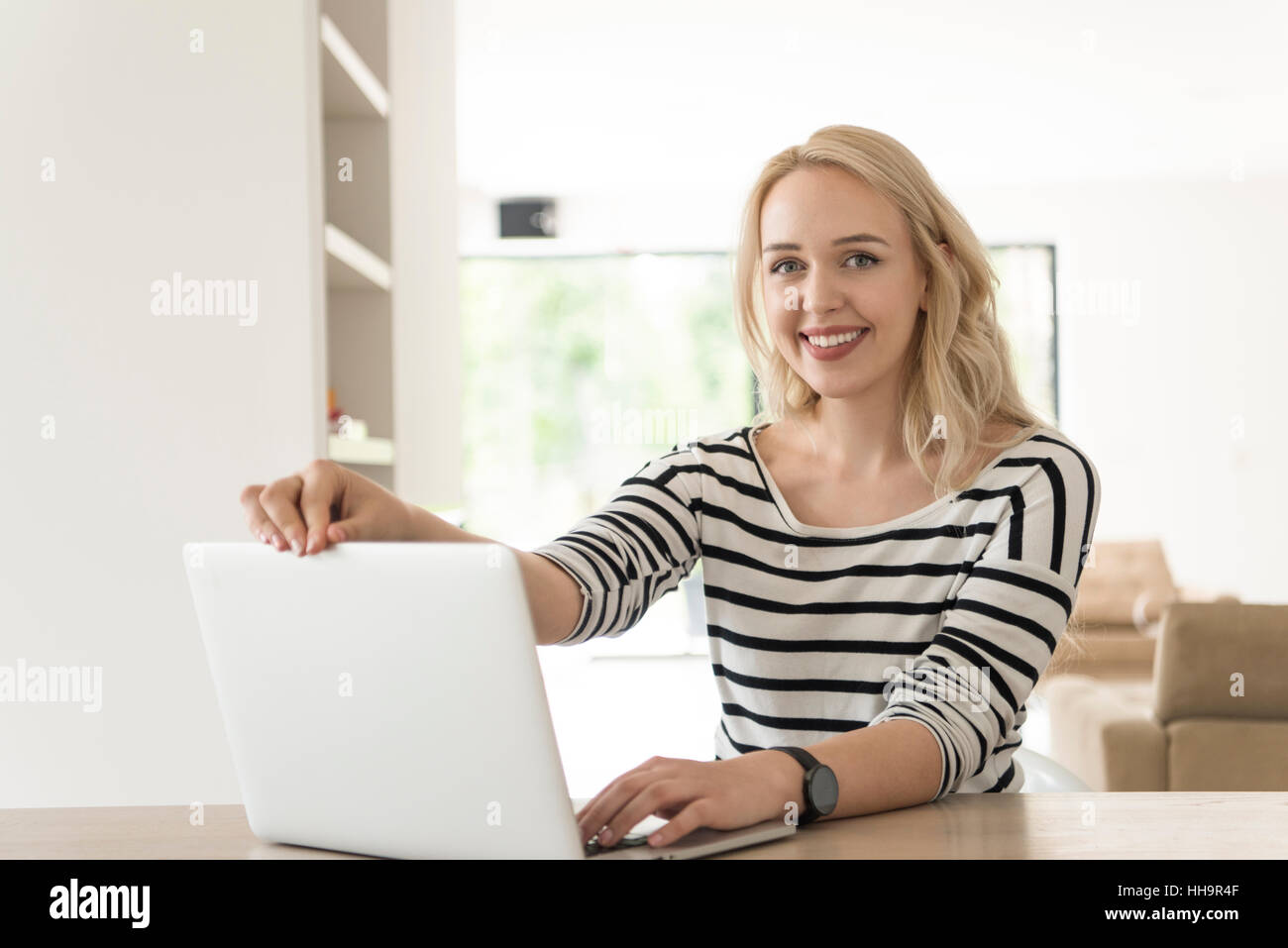 Young woman with her laptop computer in her luxury modern home, smiling ...