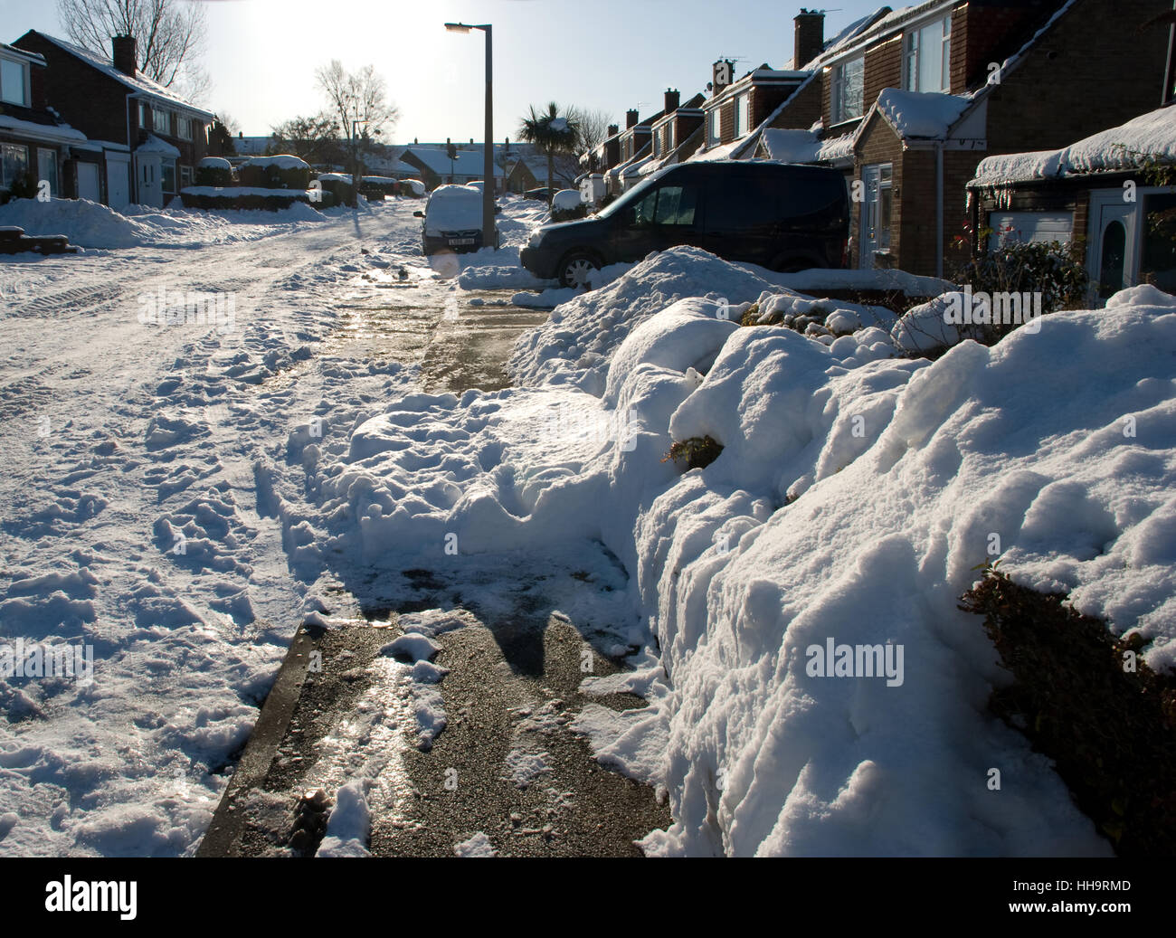 Access road on housing estate under thick snow and cleared areas with ...
