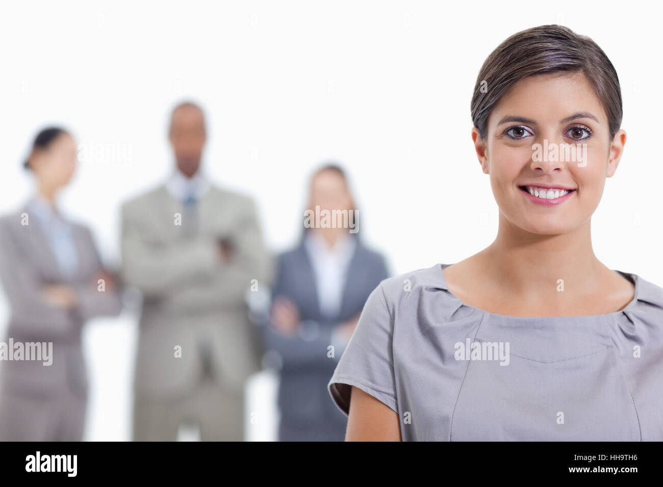 Big close-up of a businesswoman smiling and a team crossing their arms ...