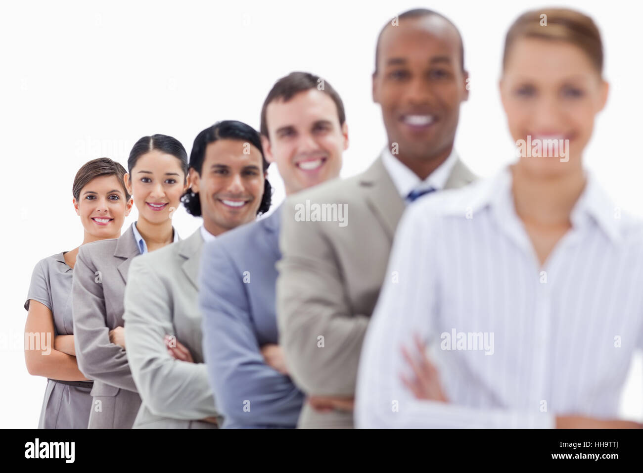 Close-up of smiling workmates dressed in suits crossing their arms in a ...
