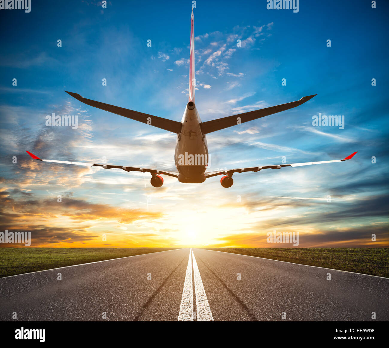 Passenger plane fly up over take-off runway at sunset. Dramatic sky on ...