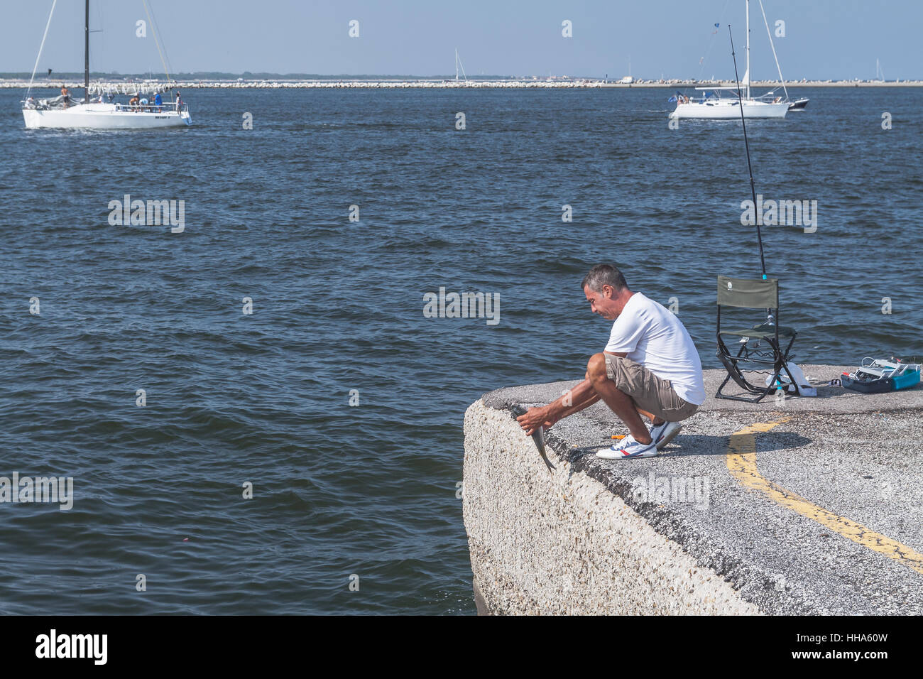Man catch a fish Fishing from the pier or fishing wharf with fishing ...