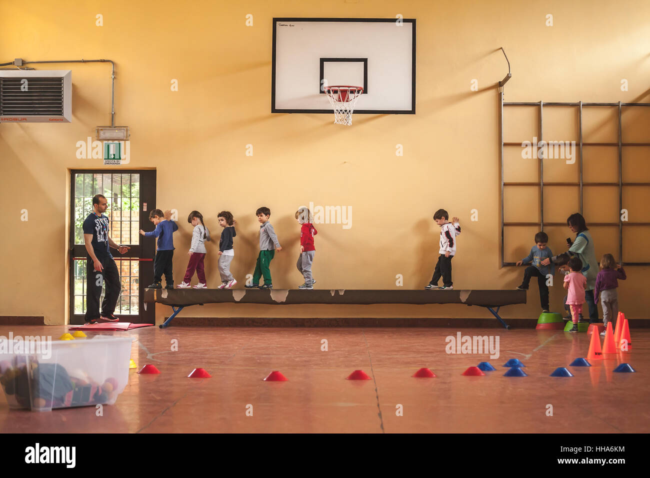 Inside the kindergarten gym with sport instructor learning kids to walk ...