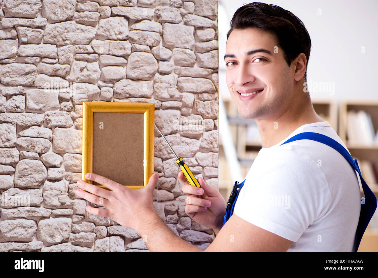 Repairman putting picture frame onto wall Stock Photo - Alamy