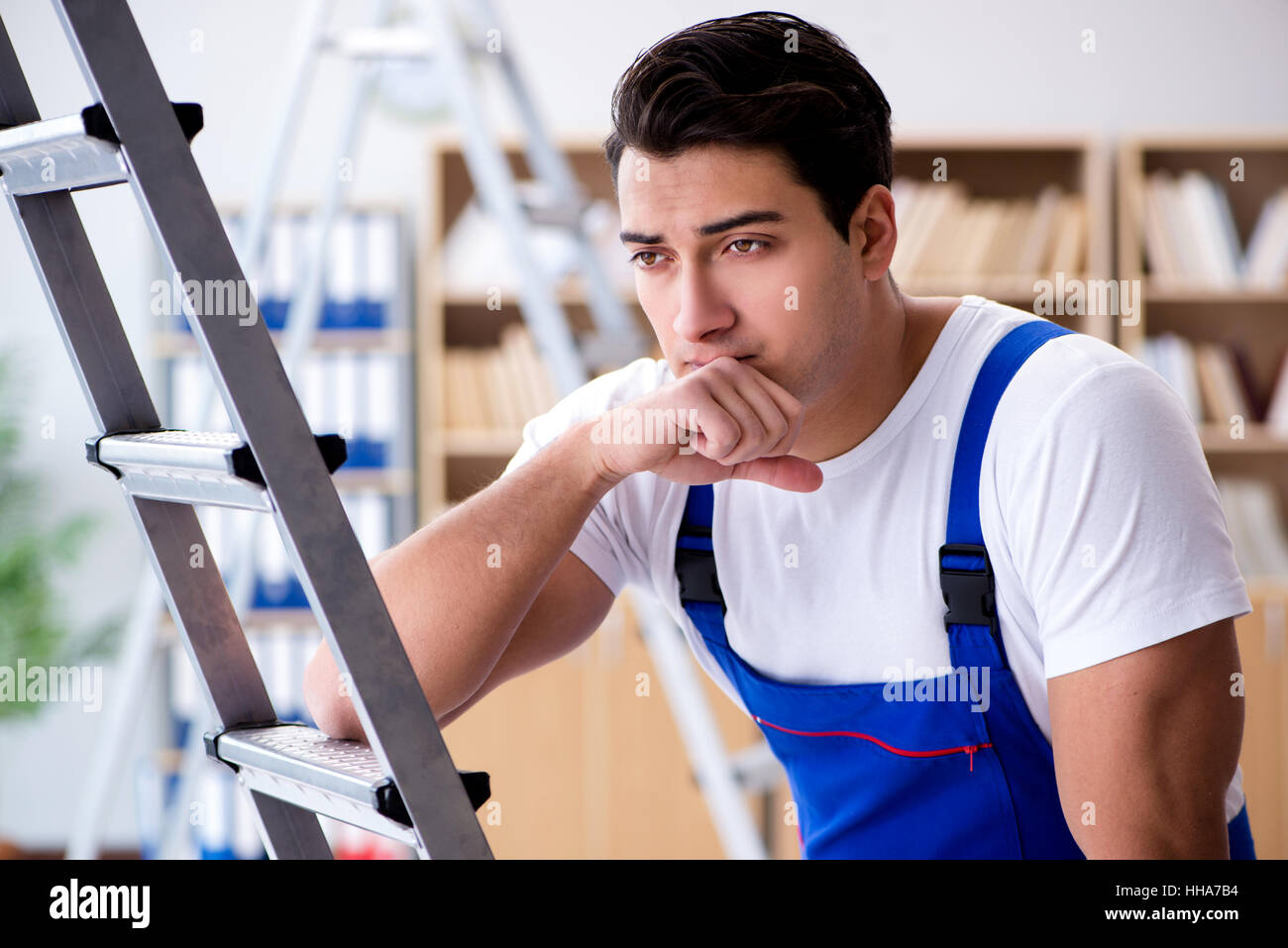 Sad repairman leaning against ladder Stock Photo - Alamy