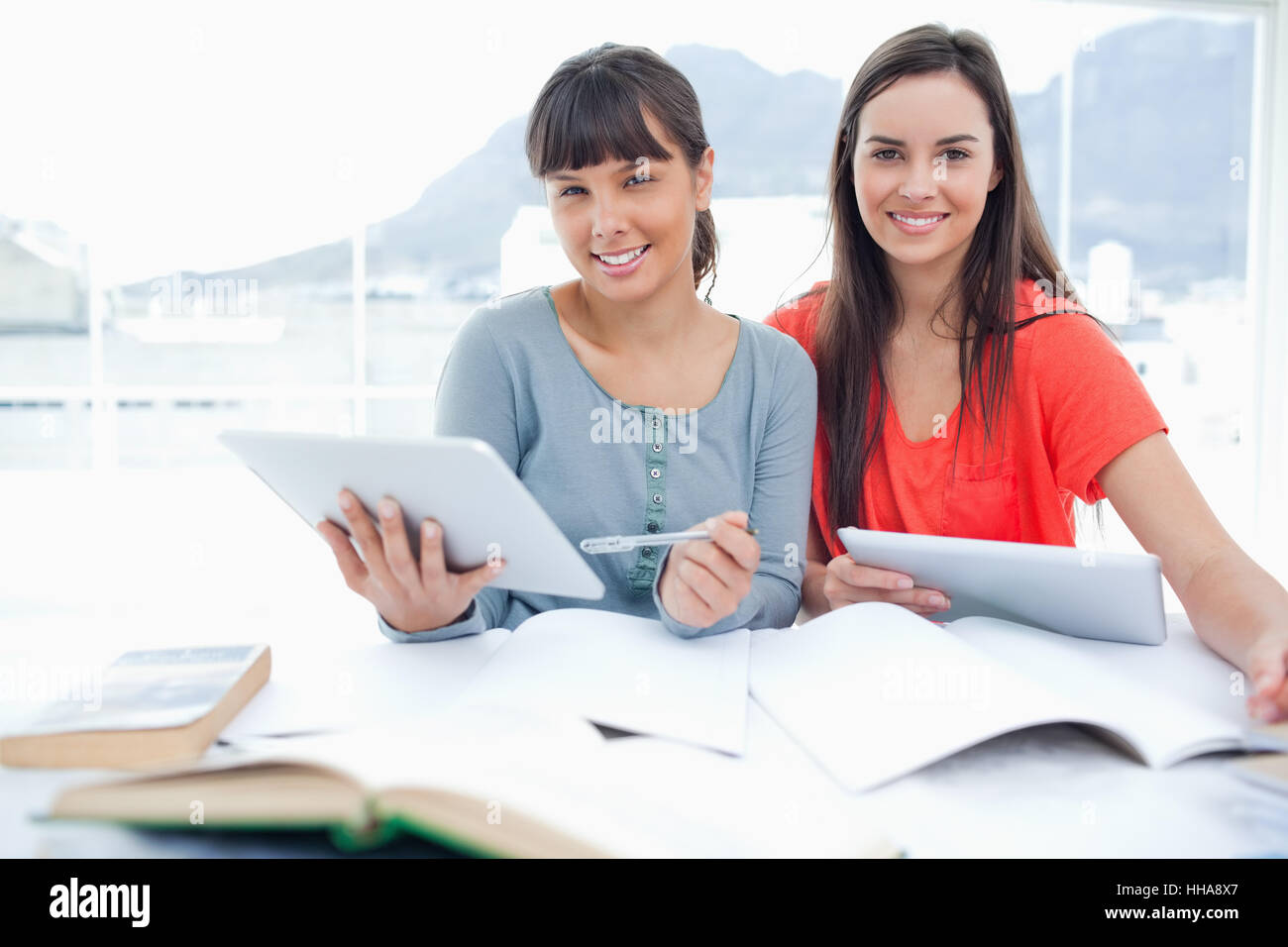 A couple of smiling students with tablets in their hands as they both ...