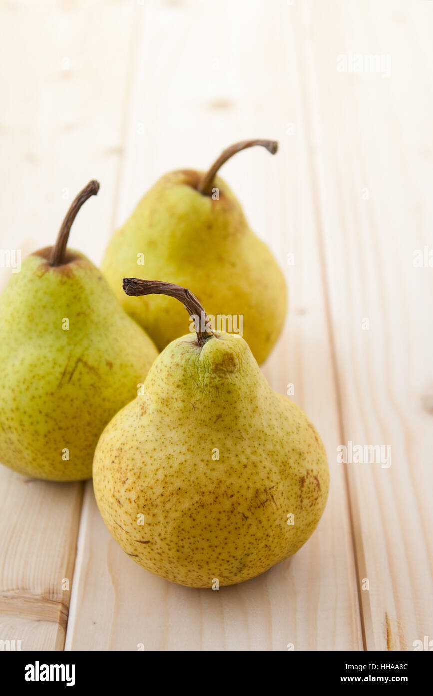 Three green pears on clear wood table Stock Photo - Alamy
