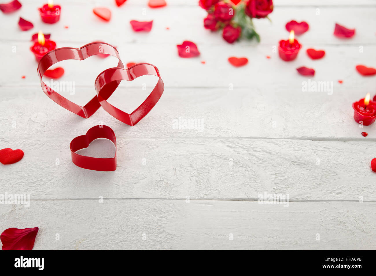 Red metal love hearts with fabric rose petals on a wood background ...