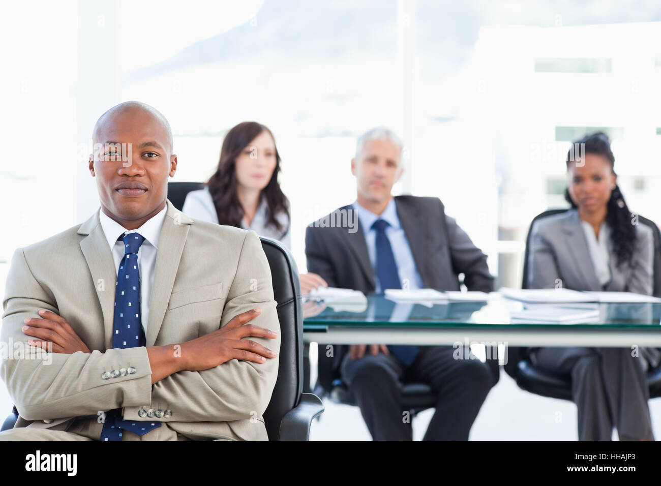 Young executive almost smiling and crossing his arms while his team is ...