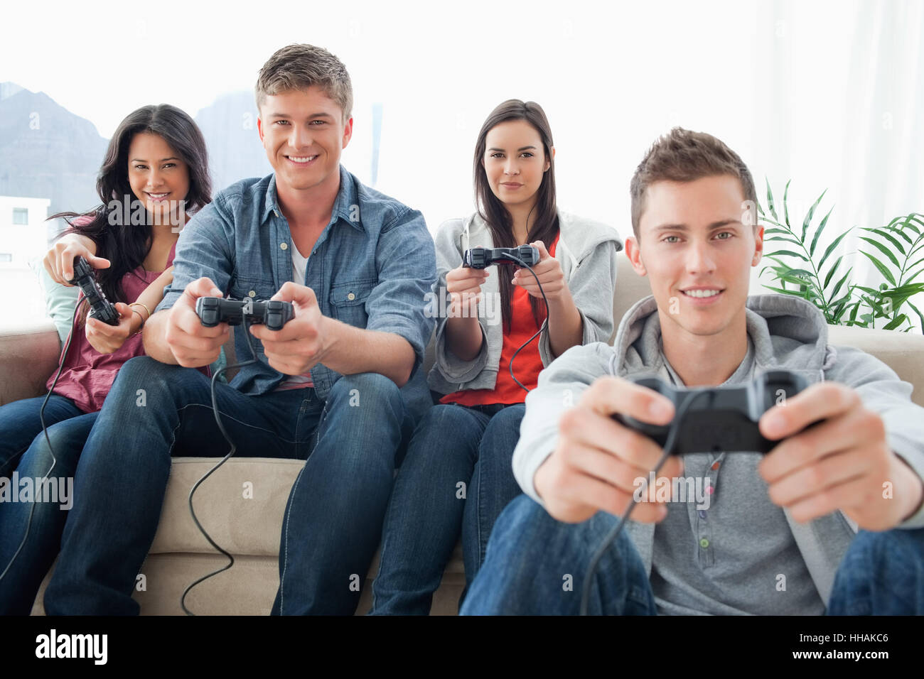 A smiling group of friends playing together on a console while looking ...