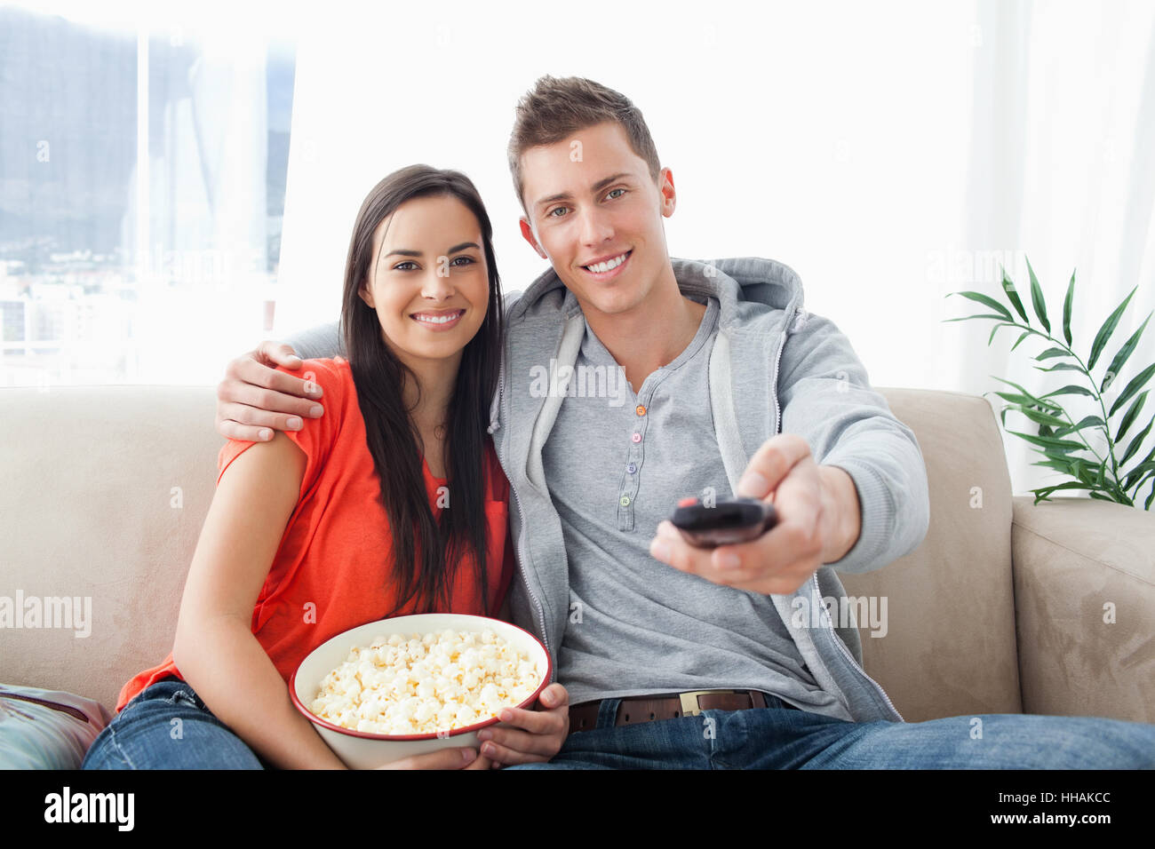 A smiling couple holding each other as they change the channel and look ...