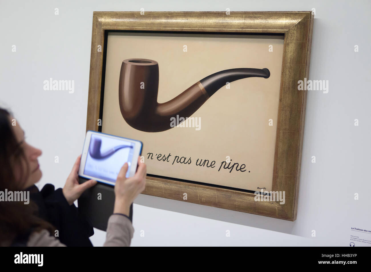 Visitor uses her tablet to photograph the painting 'La trahison des ...