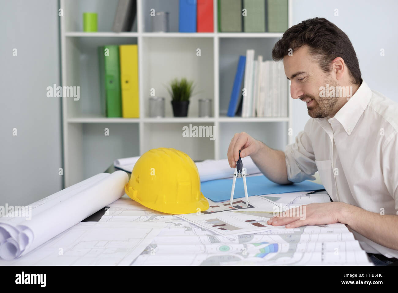 Architect working on his projects papers with compass Stock Photo - Alamy