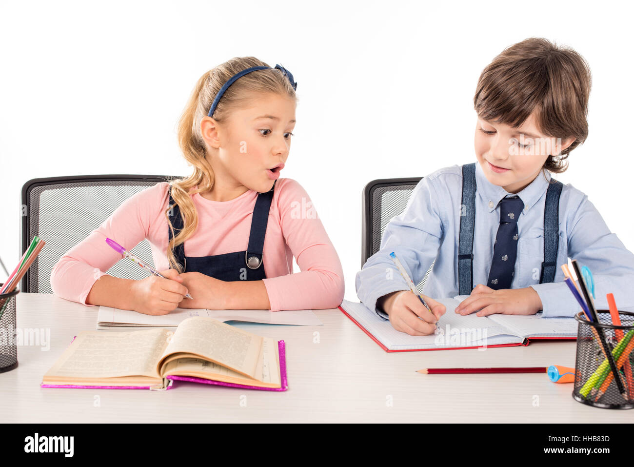 Shocked schoolgirl looking at classmate's notebook isolated on white ...
