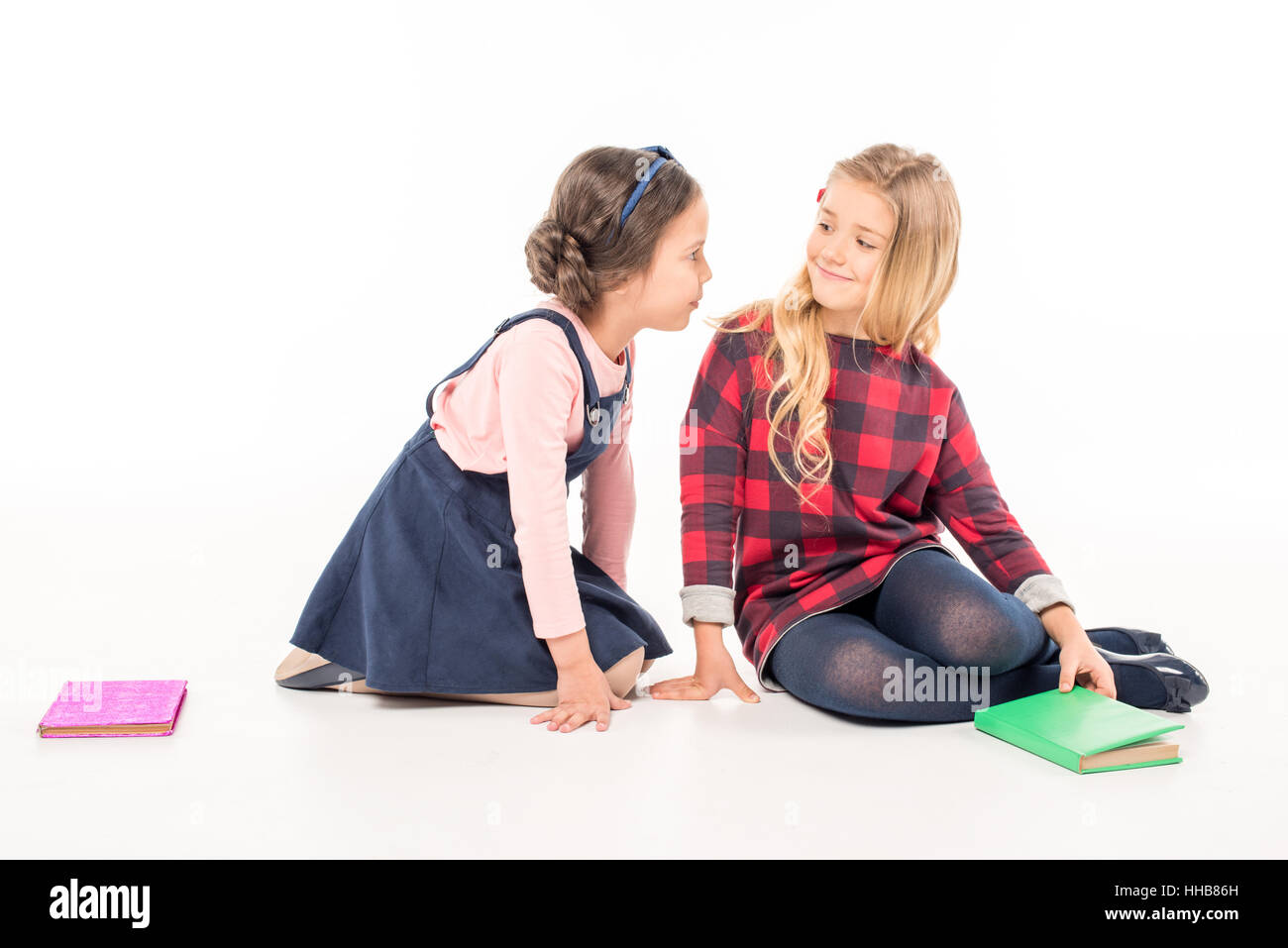 Two schoolgirls sitting with books and talking on white Stock Photo - Alamy