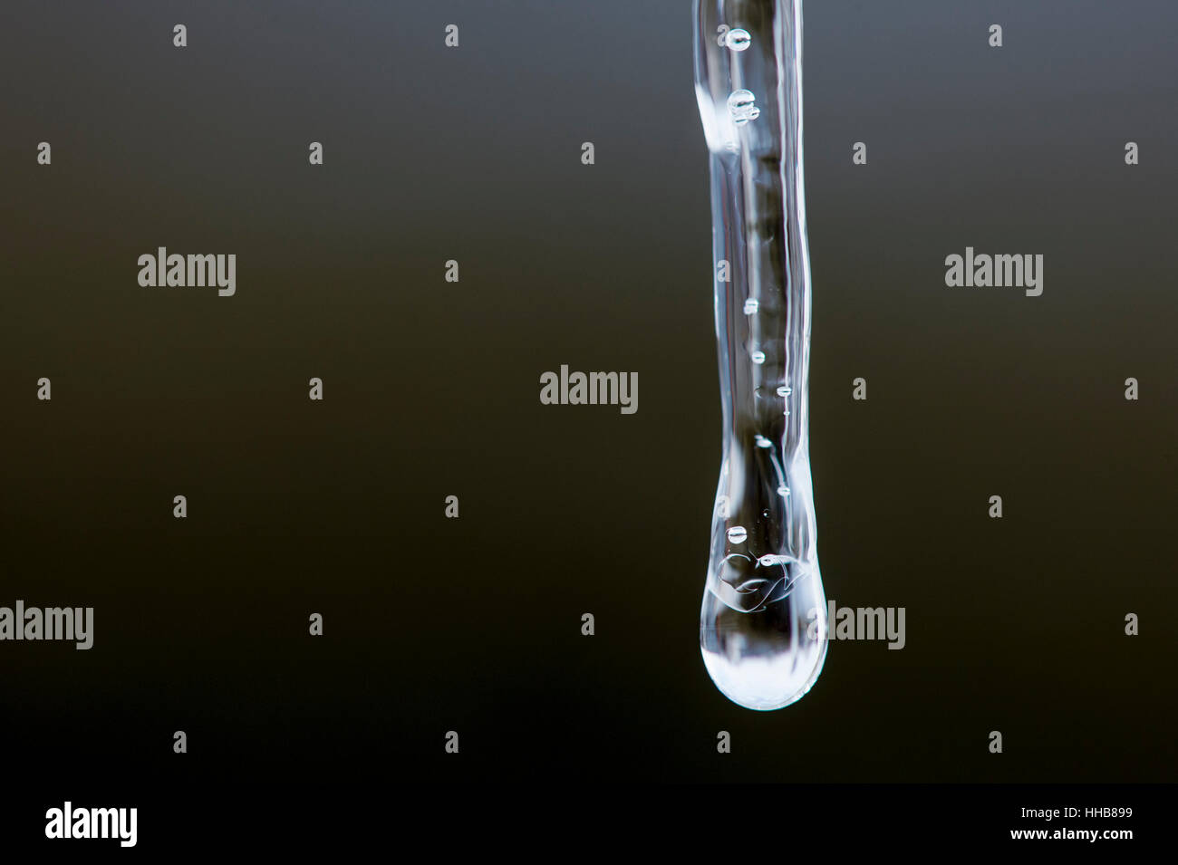 A close up of an icicle withsmooth edges in front of a dark background ...