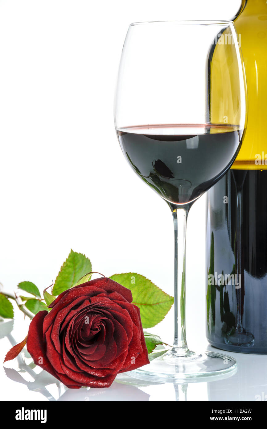 Beautiful red rose and wineglass of red wine and a bottle on a white ...