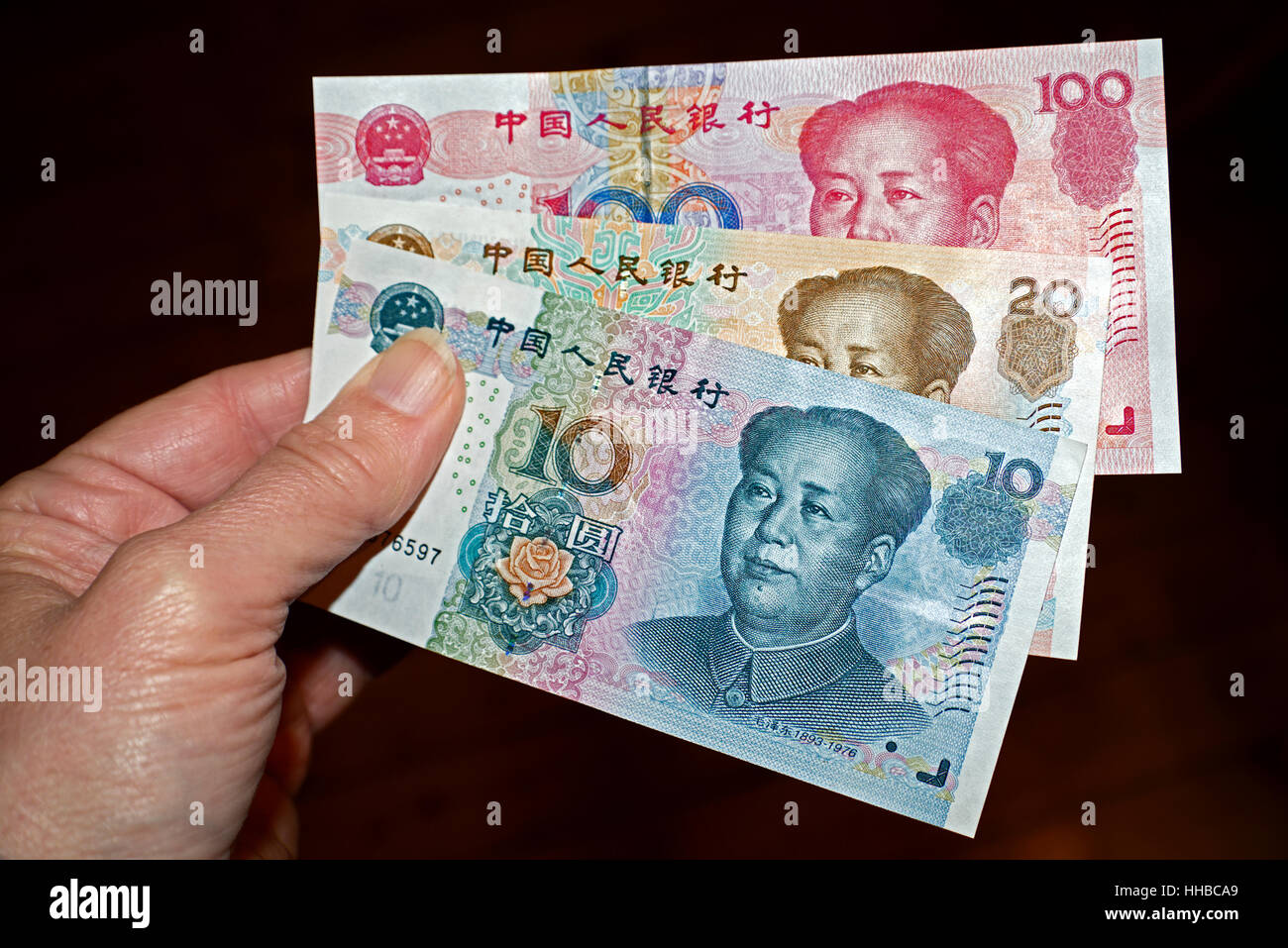Hand holding Chinese currency of 10, 20 and 100 Yuan noteswith likeness ...