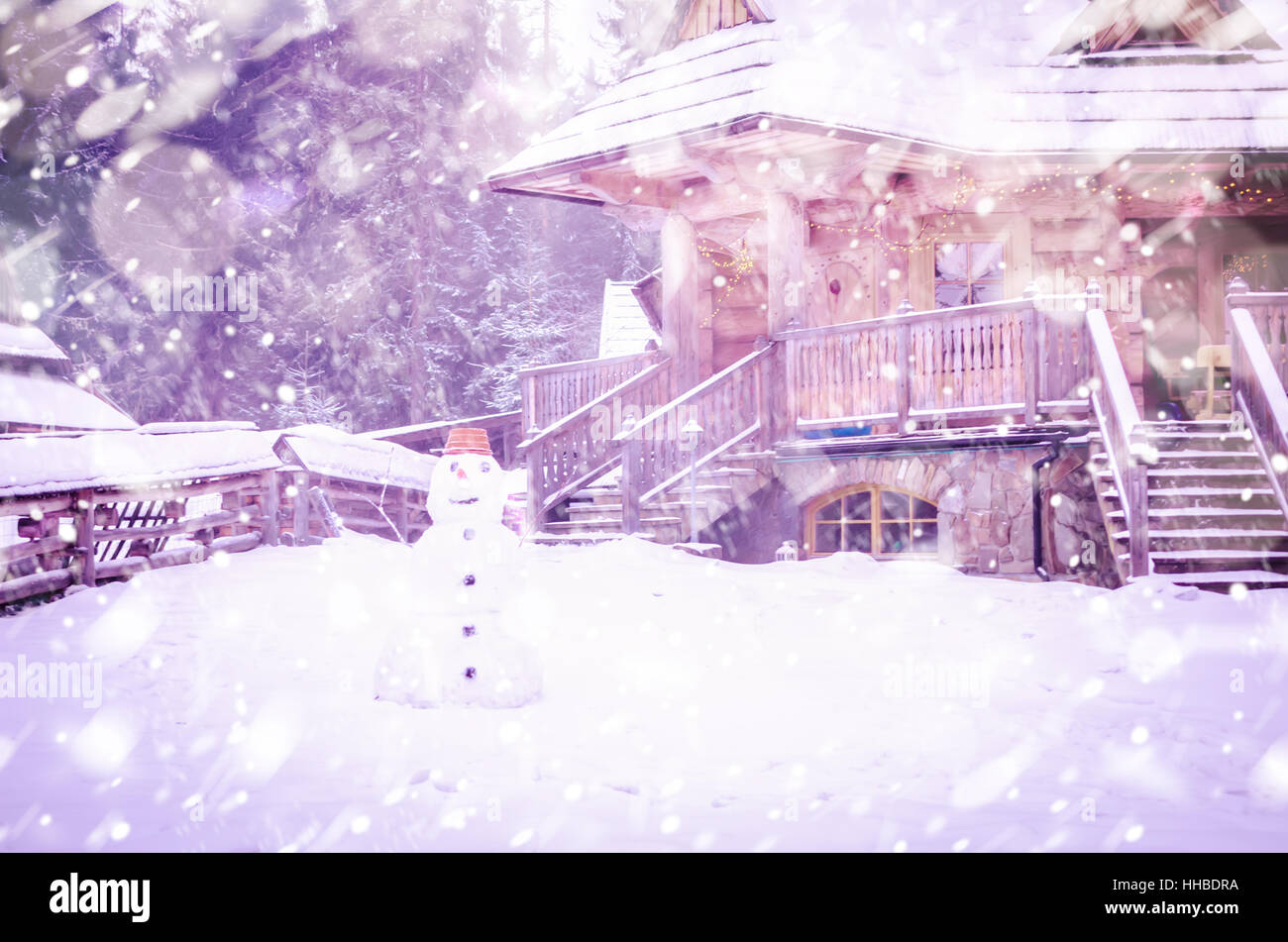 Winter snowy wooden house and a snowman in the yard. Nature scene with ...