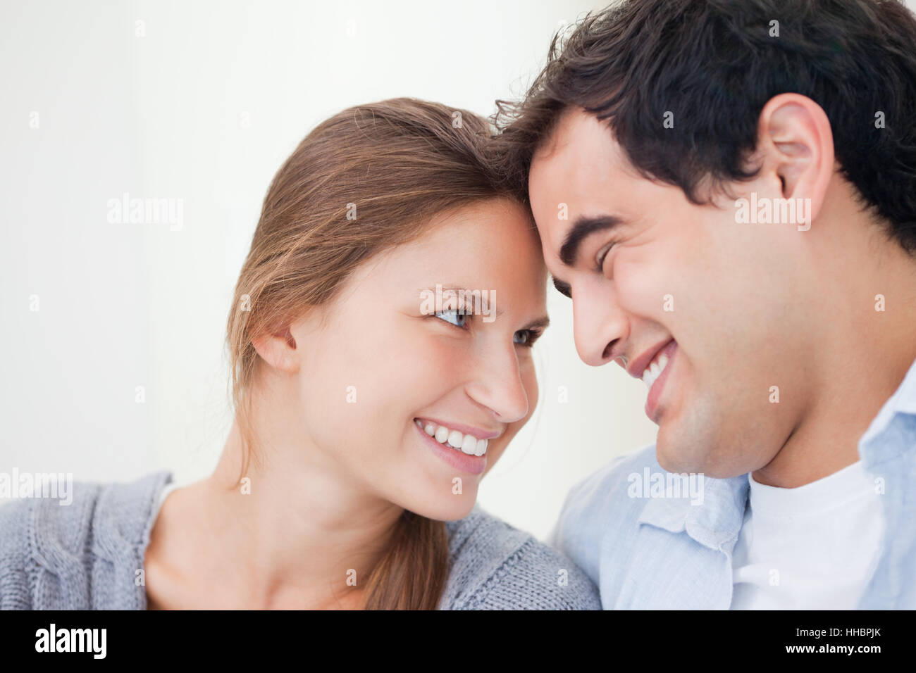 Couple smiling while touching forehead against grey background Stock ...