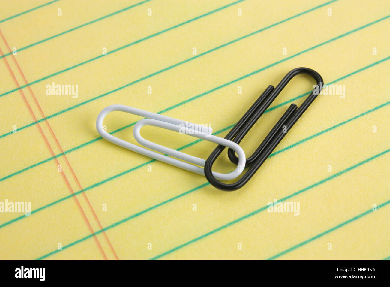 Black and white paper clips connected on a legal pad of paper Stock ...