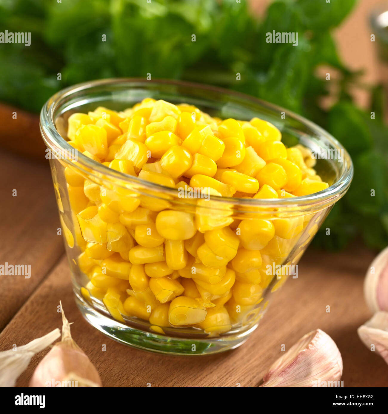 Sweetcorn grains in glass bowl with garlic cloves and watercress ...