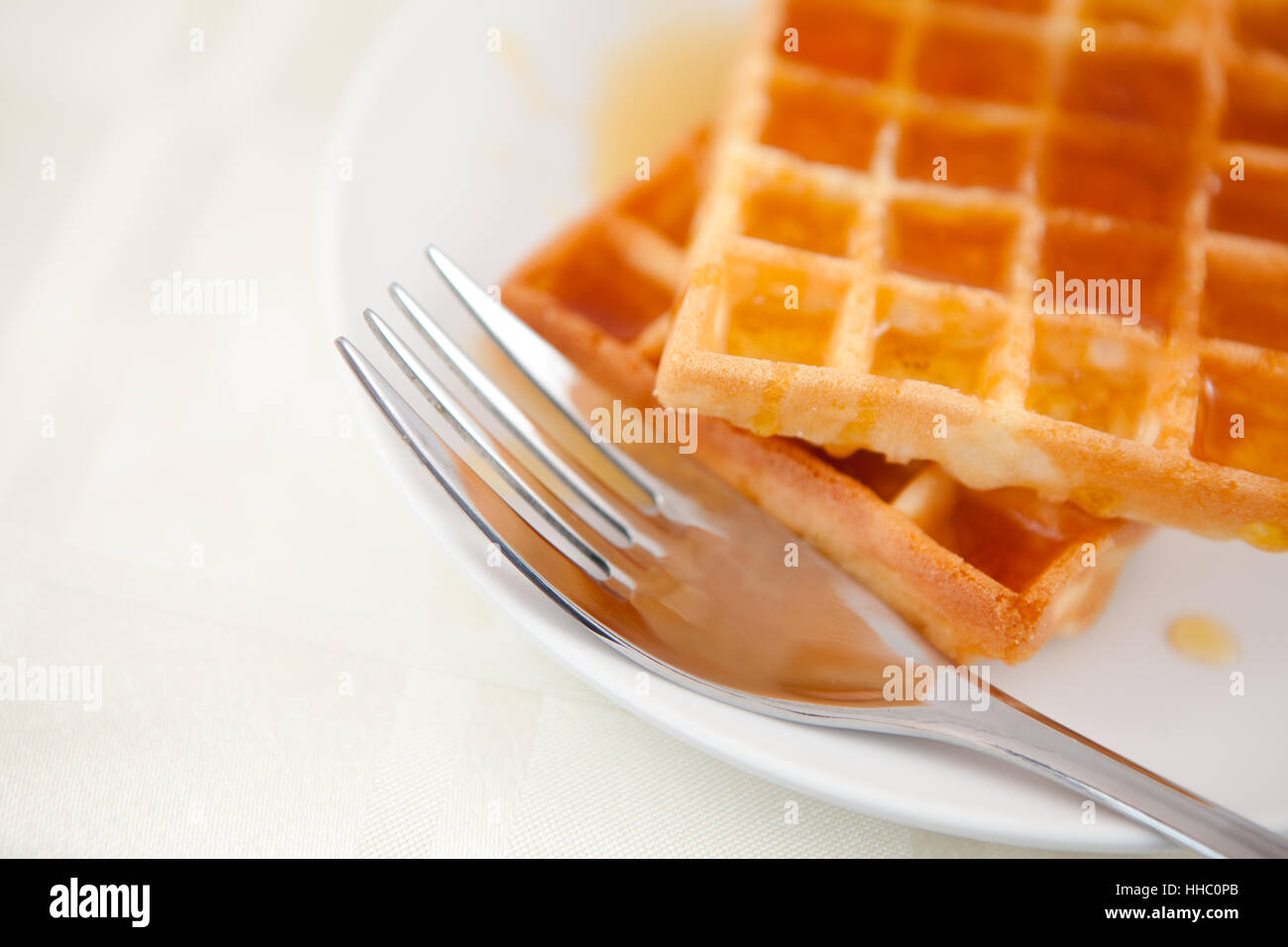 Two waffles and a fork on a saucer on a table Stock Photo - Alamy