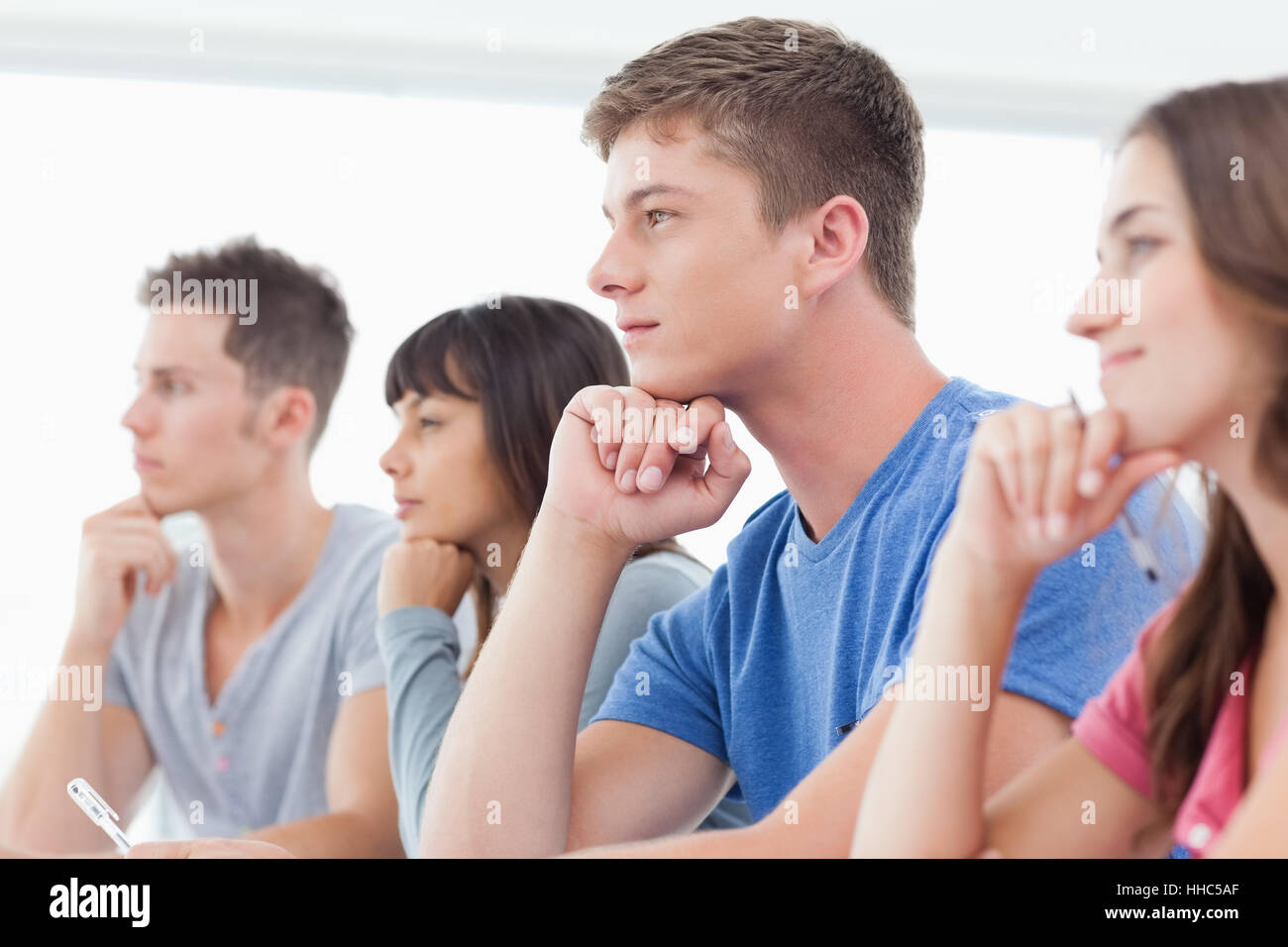 A side view of a group of students thinking with hands on their chins ...
