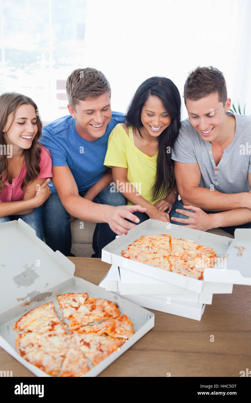 A group of friends with some pizza as one guy reaches out for a slice ...