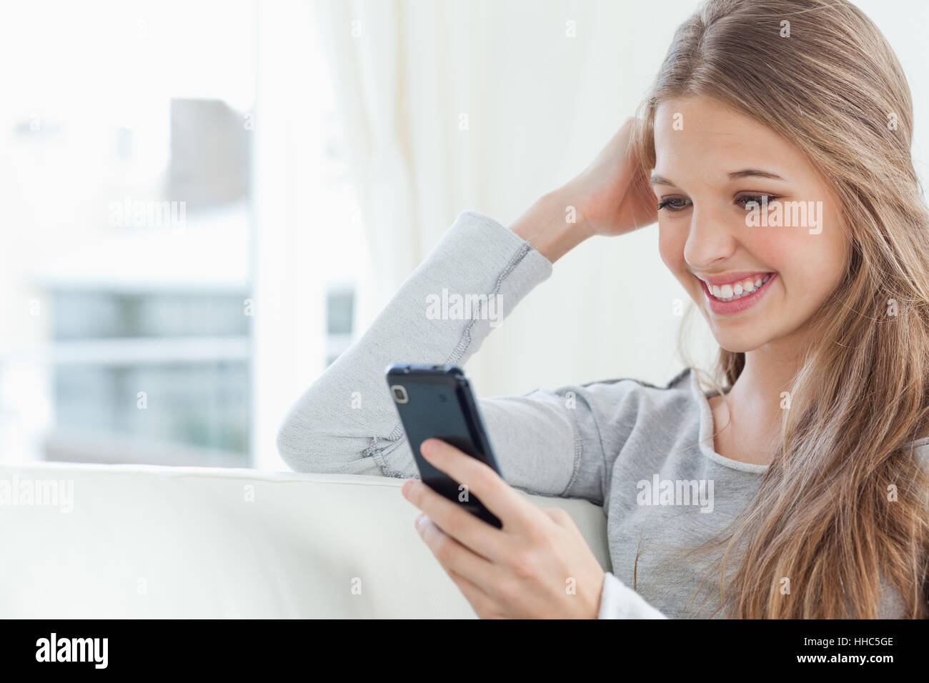 A girl with her mobile in her hand as she smiles Stock Photo - Alamy