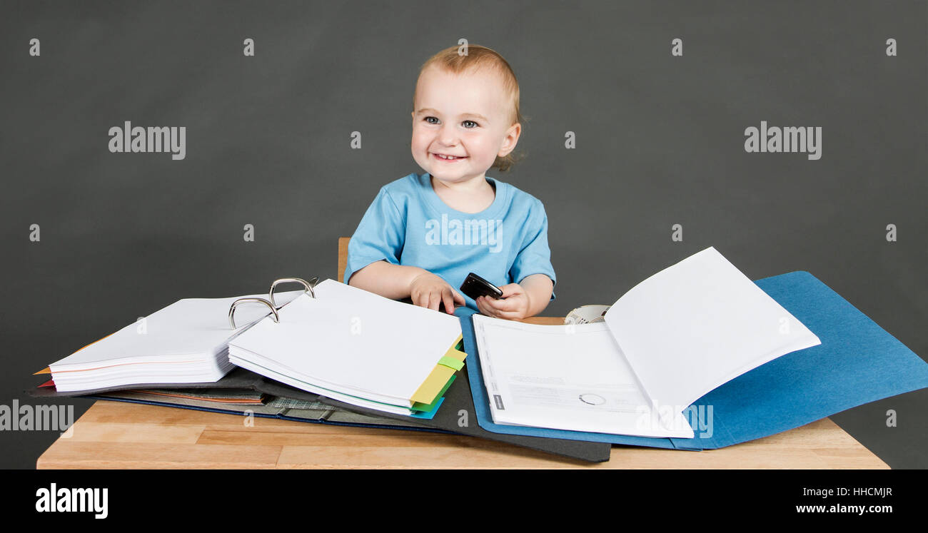 baby with paperwork at wooden desk in grey background Stock Photo - Alamy