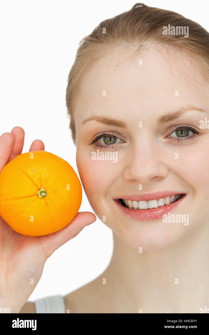 Fair-haired woman presenting an orange against white background Stock ...