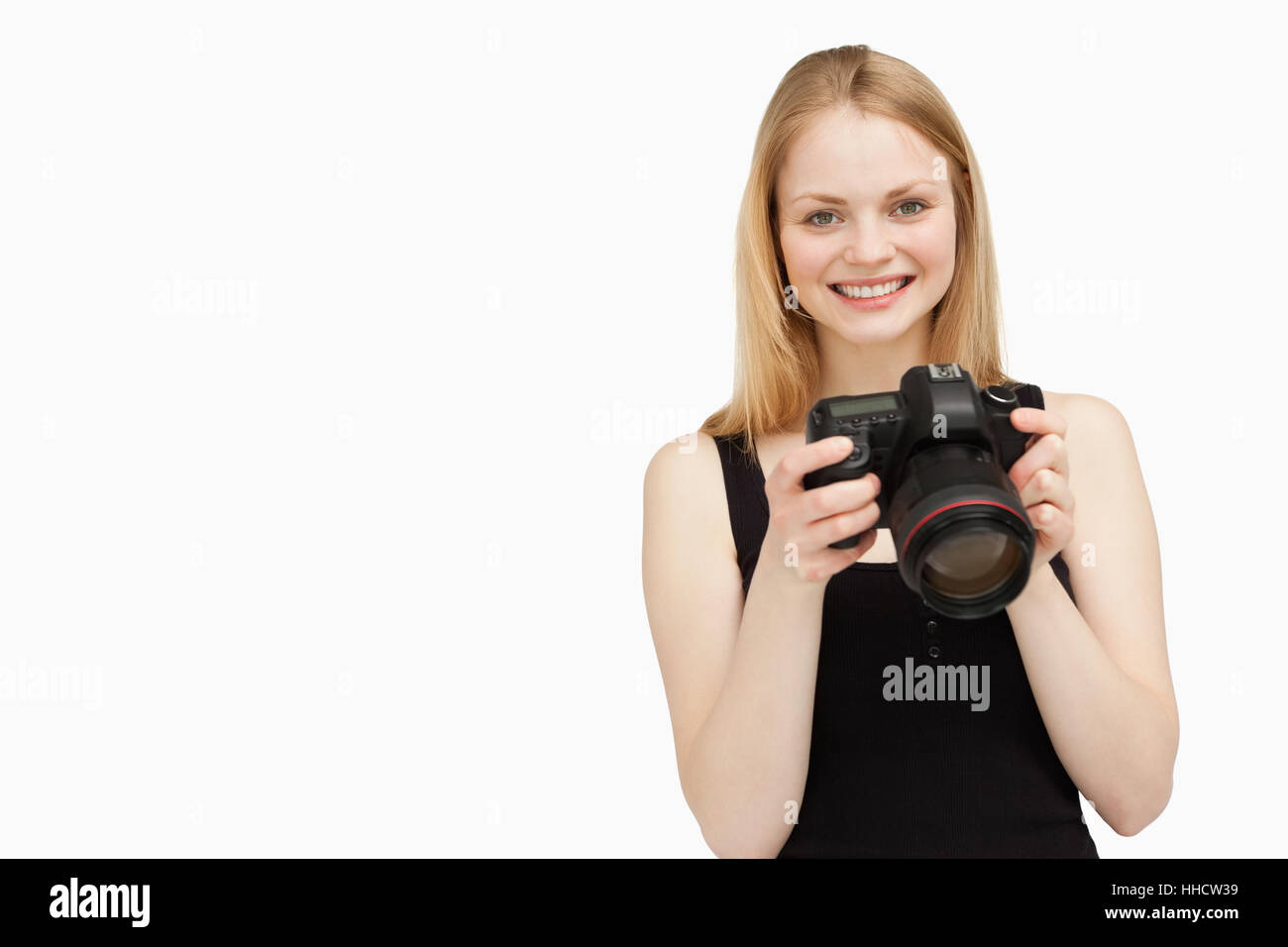 Woman holding a SLR camera while smiling against white background Stock ...