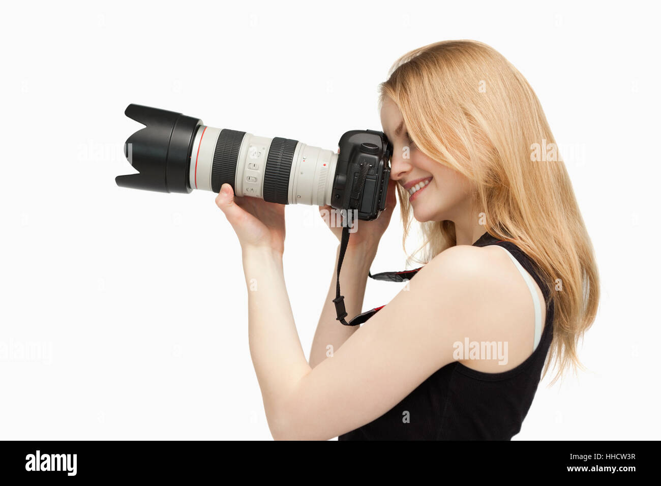 Woman smiling while holding a SLR camera against white background Stock ...