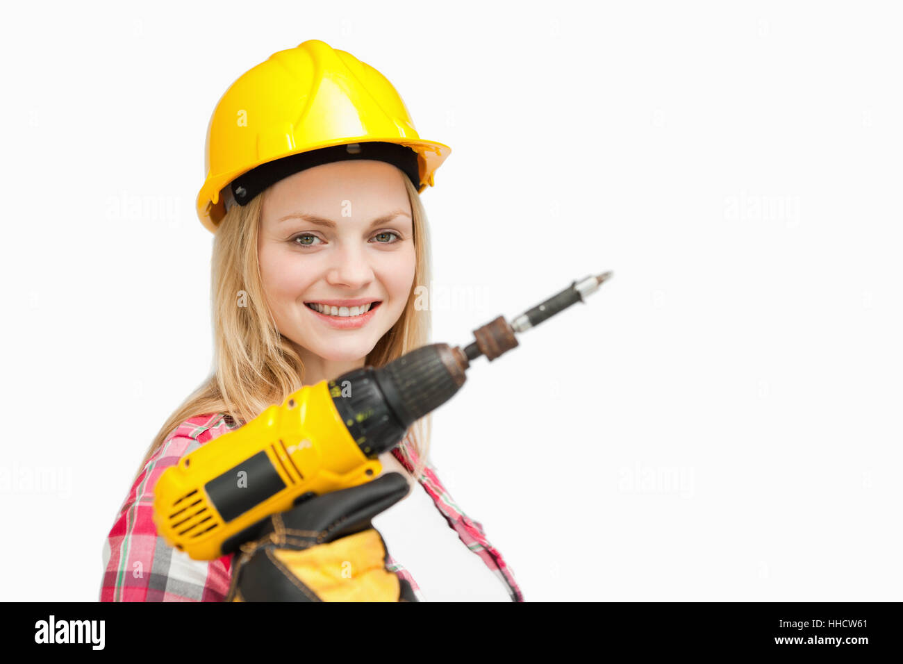 Woman holding an electric screwdriver while smiling against white ...