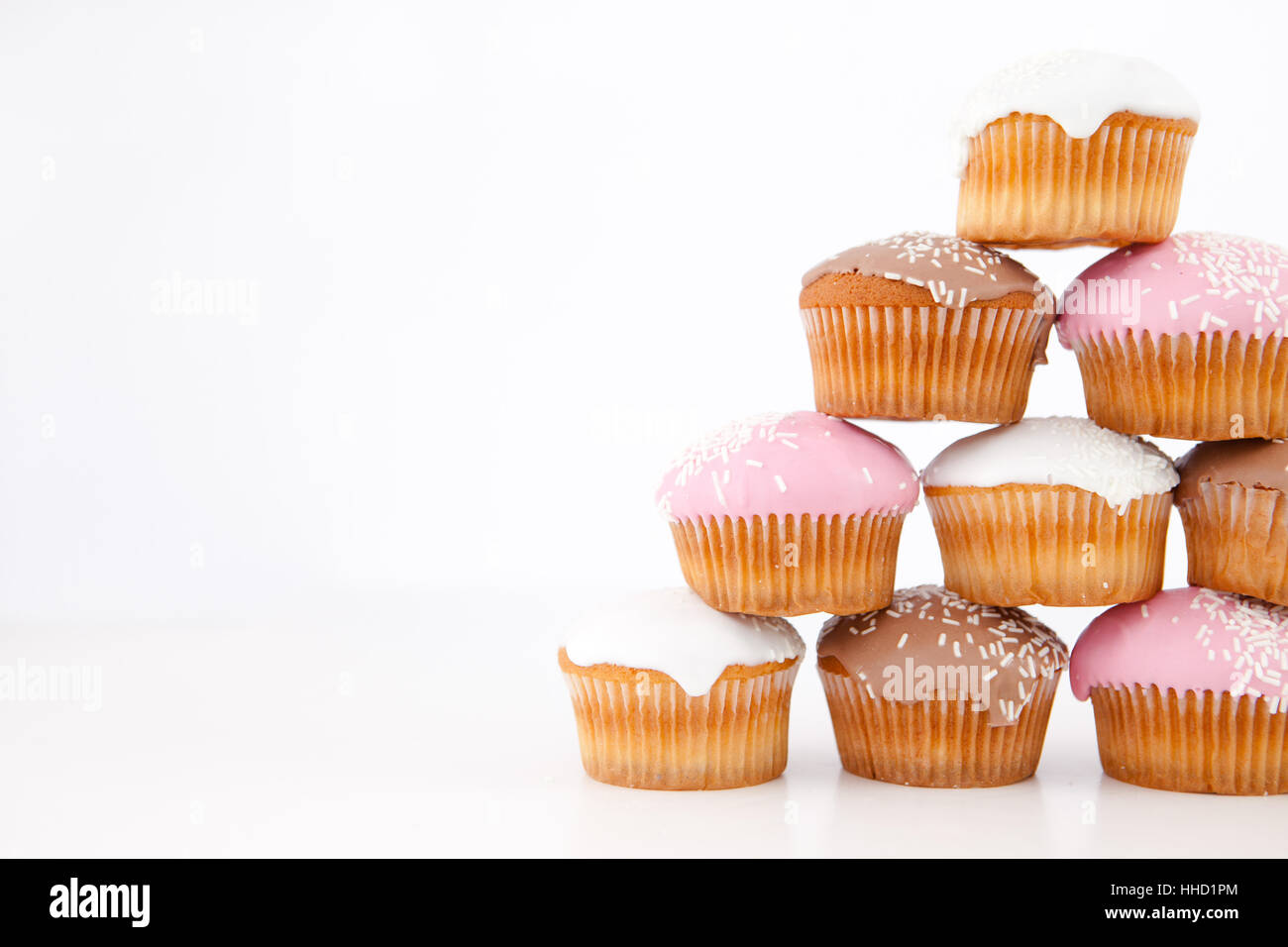 Pyramid of many muffins with icing sugar against a white background ...