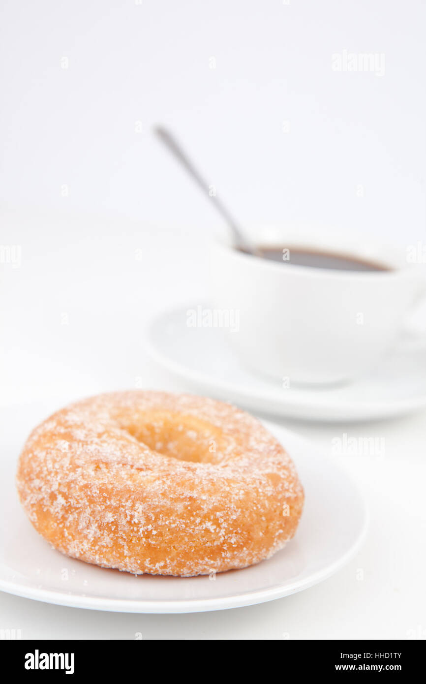 Doughnut with icing sugar and a cup of coffee with spoon on white ...