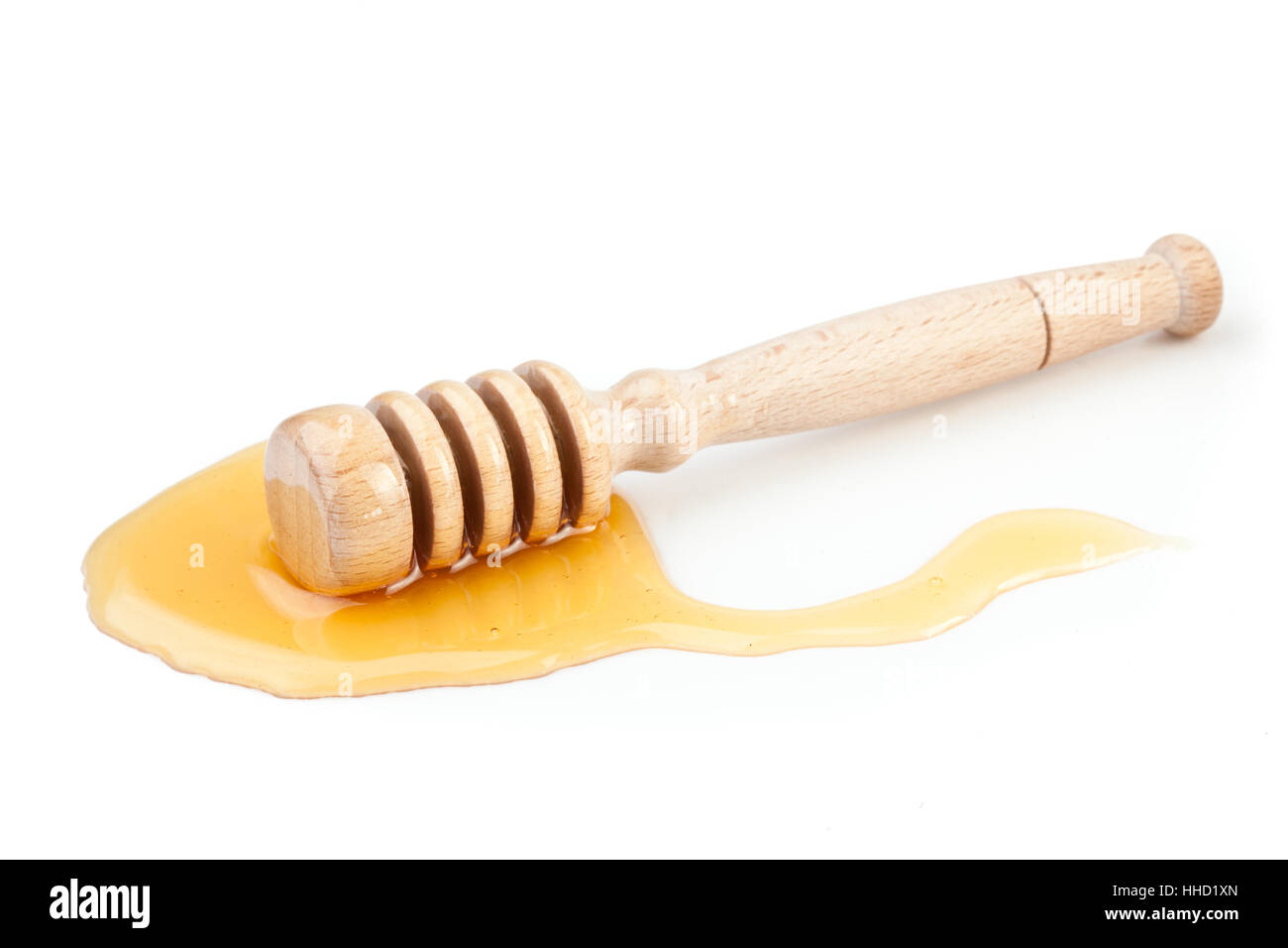 Honey dipper on the floor spilling honey against a white background ...