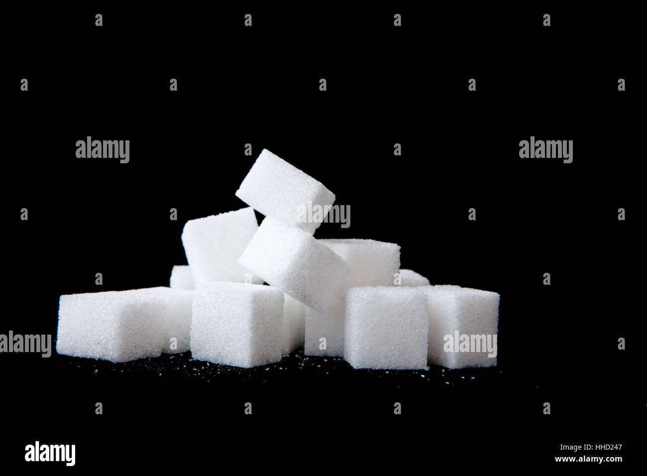 Sugar lumps piled up together against a black background Stock Photo ...
