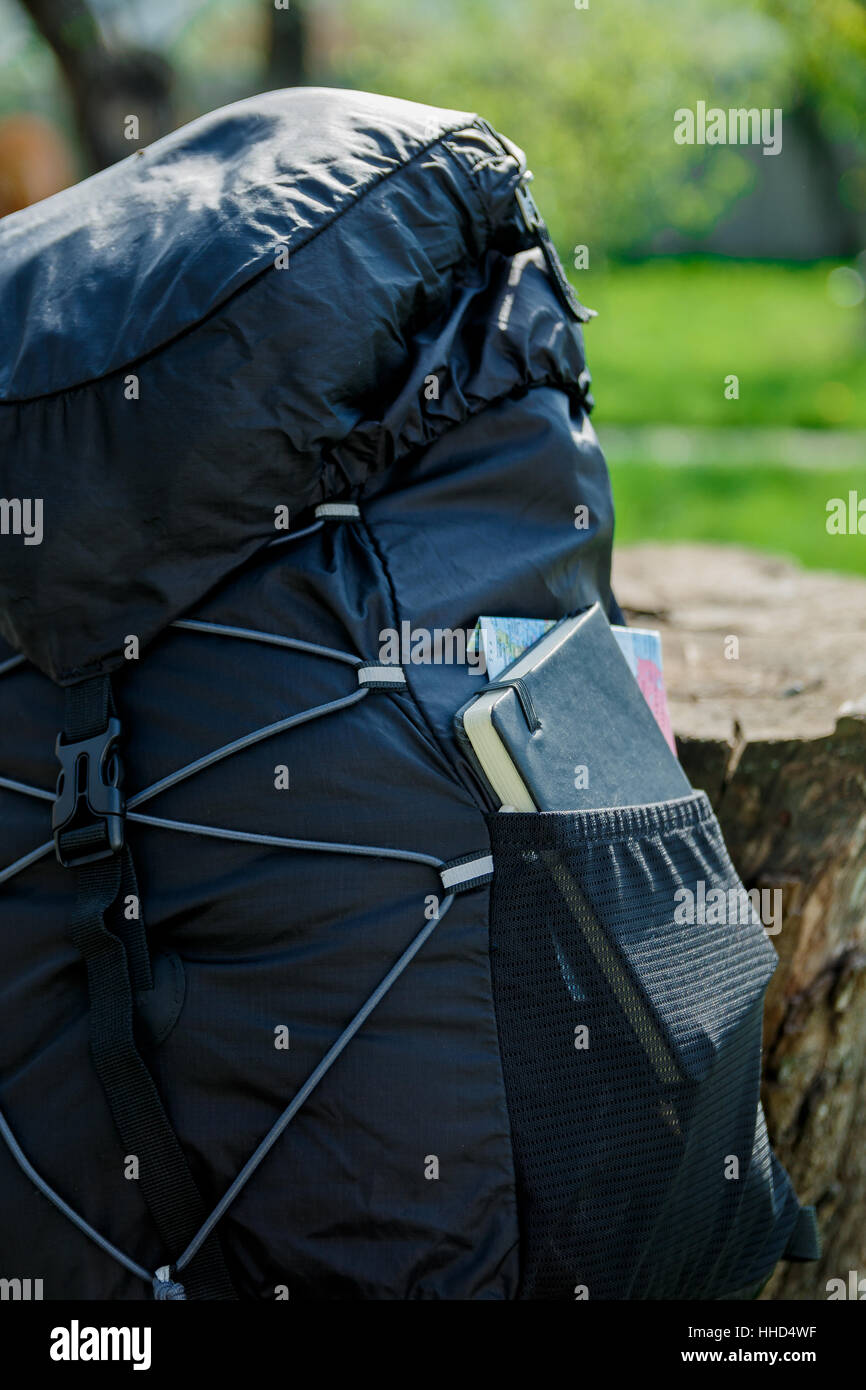 Black backpack with notebook, map and pencil outdoor. Summer. Tourism ...