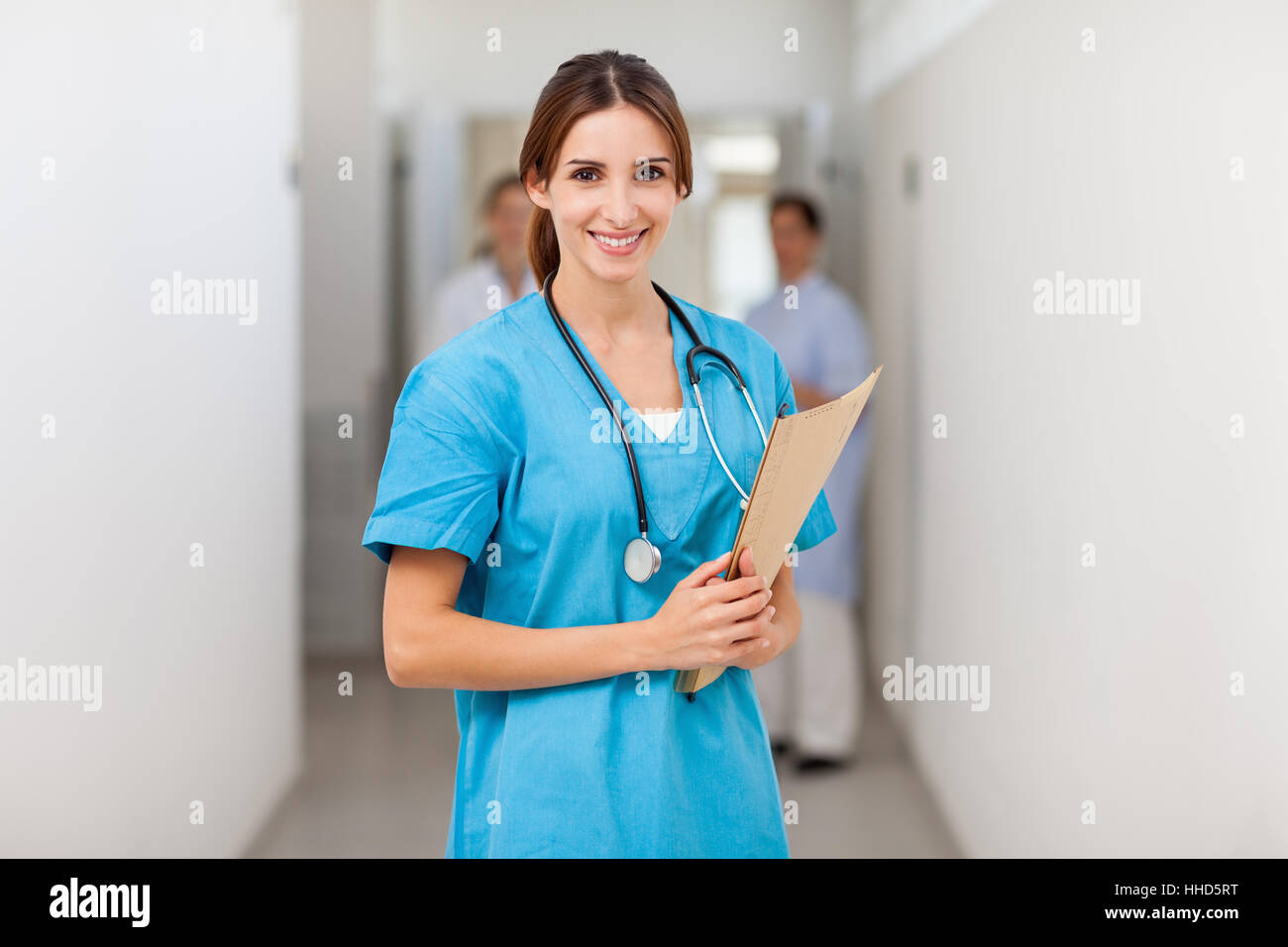 Nurse smiling while holding a file in a hallway Stock Photo - Alamy