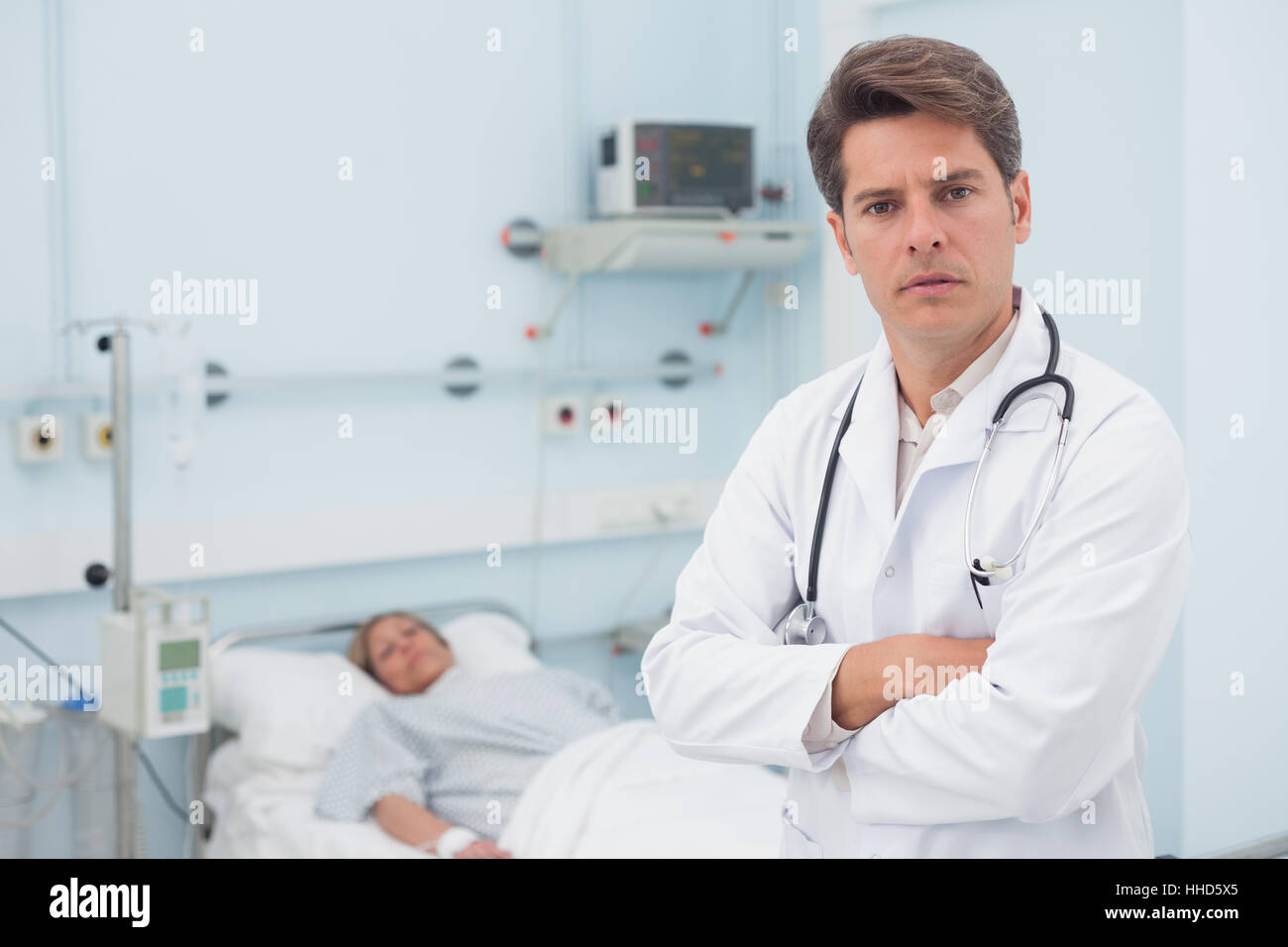 Doctor standing with crossed arms in hospital ward Stock Photo - Alamy