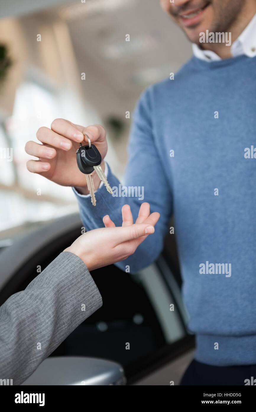 Smiling man holding keys in a car shop Stock Photo - Alamy