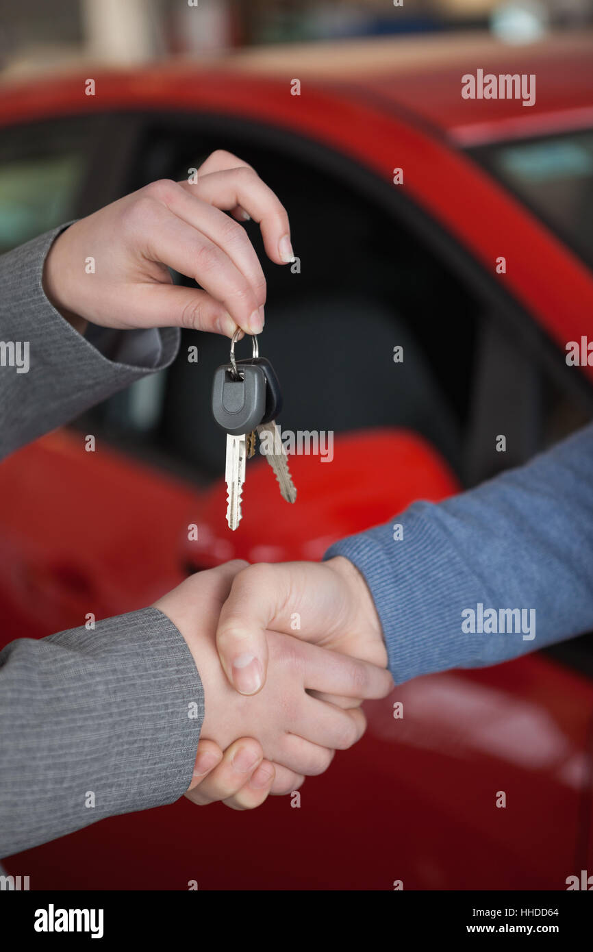 People shaking hands while holding keys in a car shop Stock Photo - Alamy