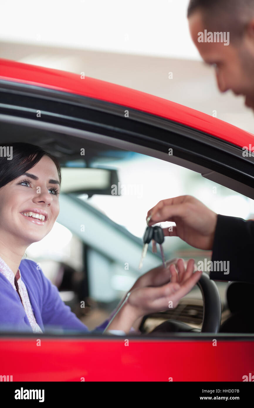 Woman smiling while receiving car keys in a car shop Stock Photo - Alamy